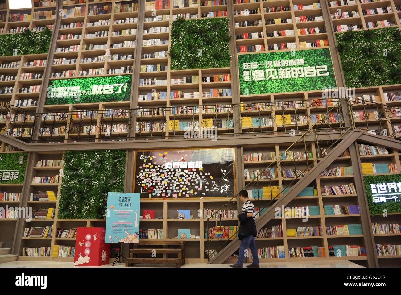 A customer reads books in front of a 10-meter-tall books wall formed by ...