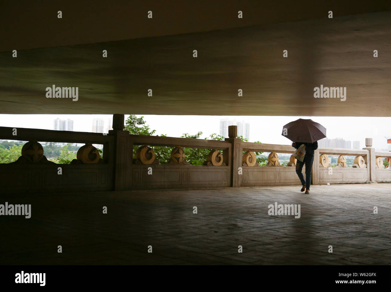 A pedestrian stoops to walk under a bridge for vehicles built closed to ...