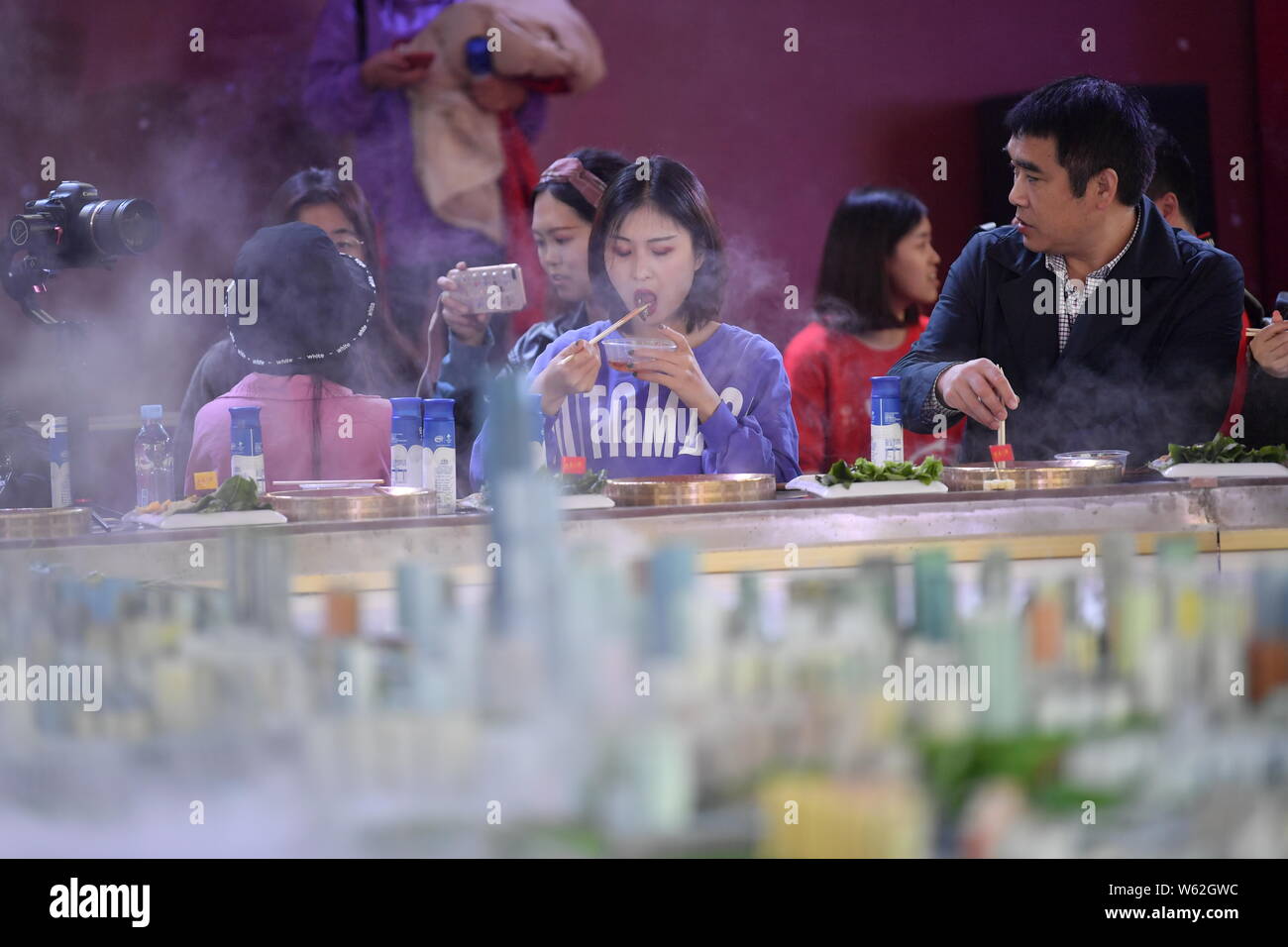 Chinese customers dine around a giant hotpot decorated with models of ...