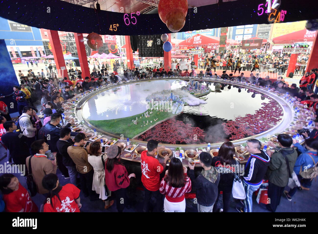Chinese customers dine around a giant hotpot decorated with models of ...