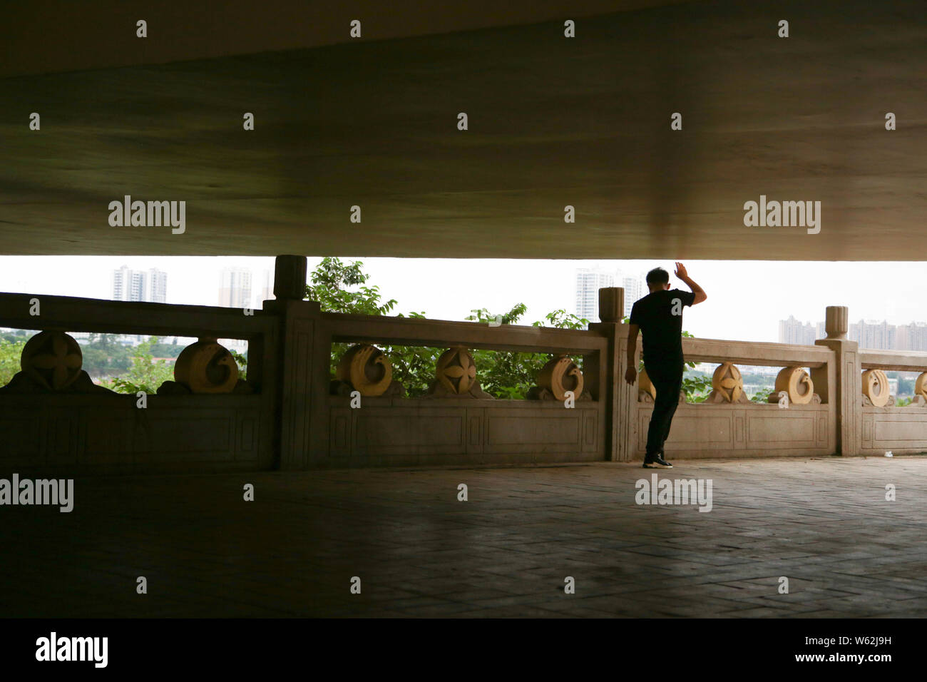 A pedestrian stoops to walk under a bridge for vehicles built closed to ...