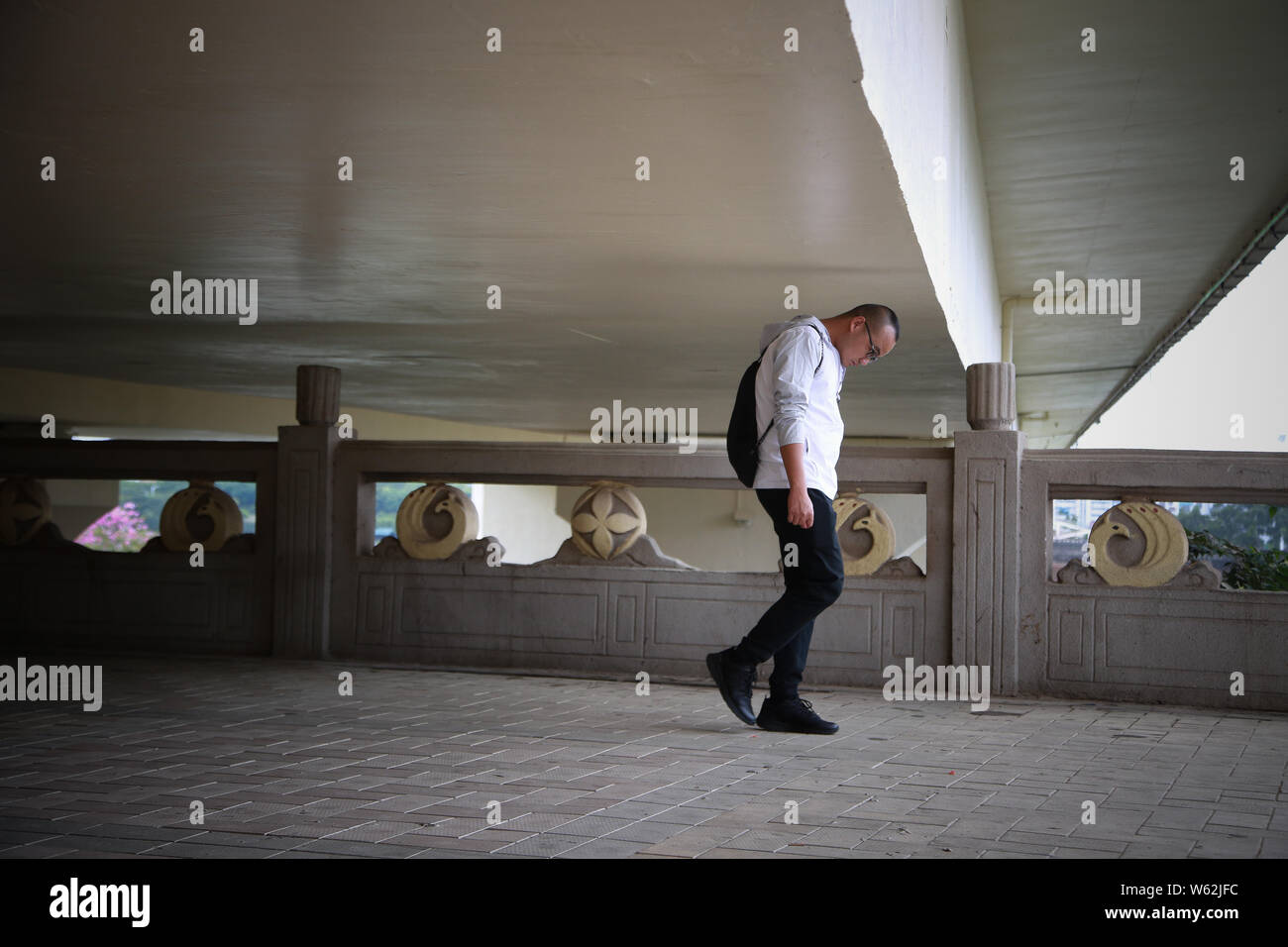 A pedestrian stoops to walk under a bridge for vehicles built closed to ...