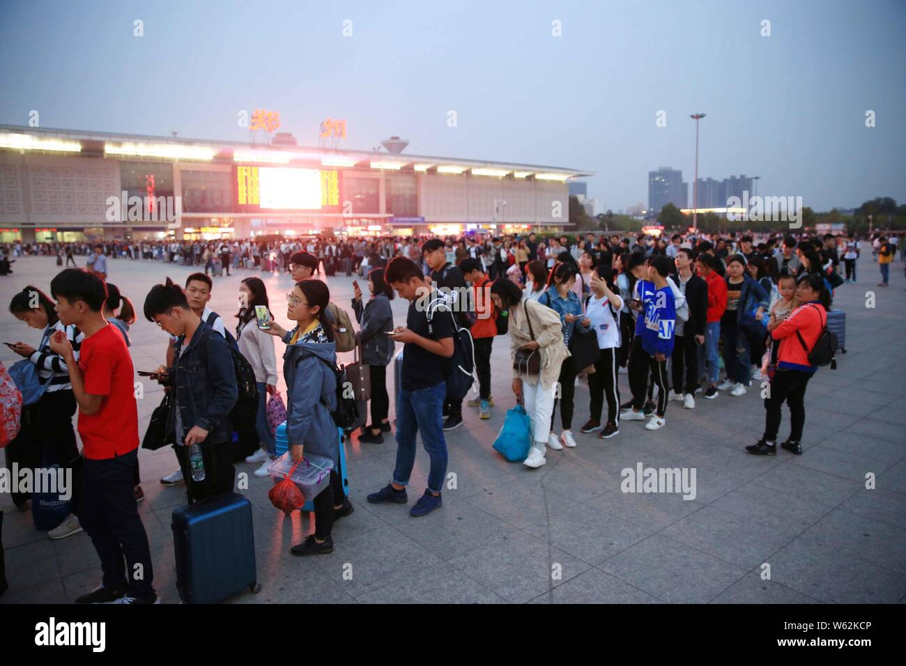 Chinese tourists and passengers queue up to enter a metro station ...