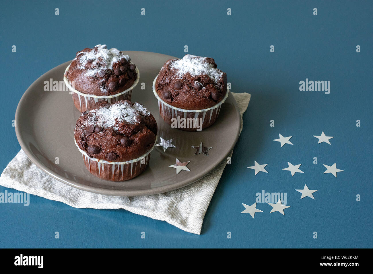 Three chocolate muffins lie on a plate against the background of a ...