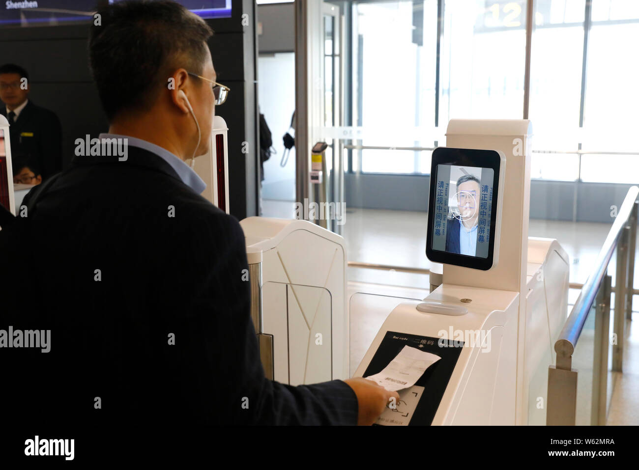 A passenger scans his boarding pass on a self-service boarding machine ...