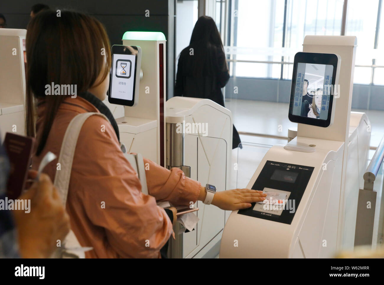 A passenger scans her boarding pass on a self-service boarding machine ...