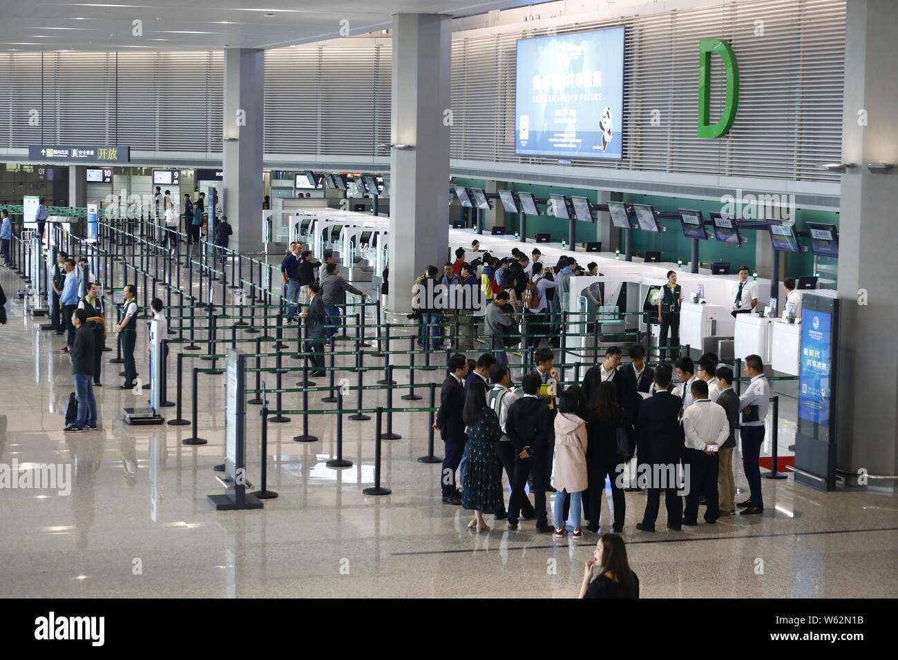 Passengers scan their boarding passes on self-service boarding machines ...