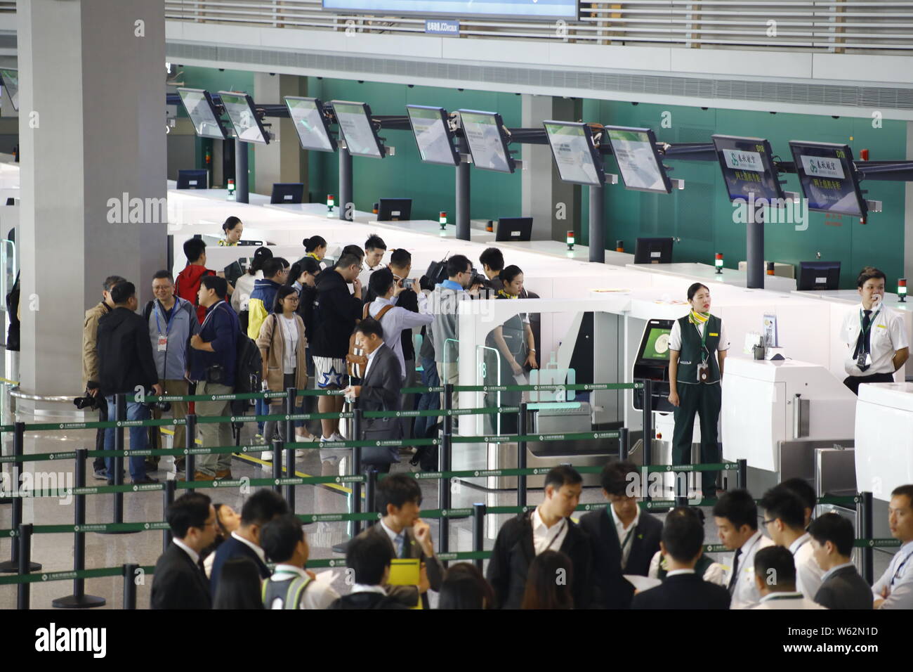 Passengers scan their boarding passes on self-service boarding machines ...