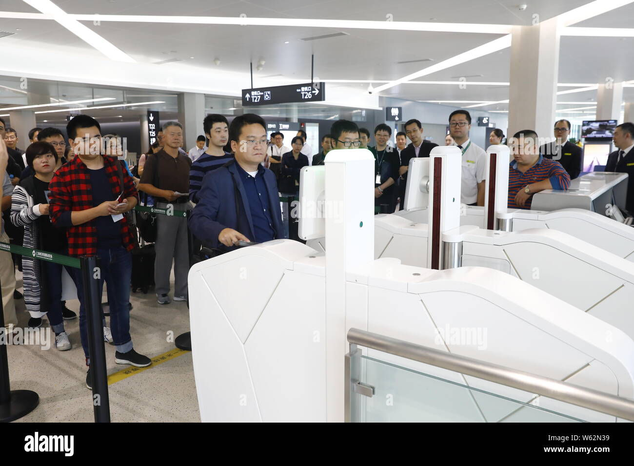 Passengers scan their boarding passes on self-service boarding machines ...