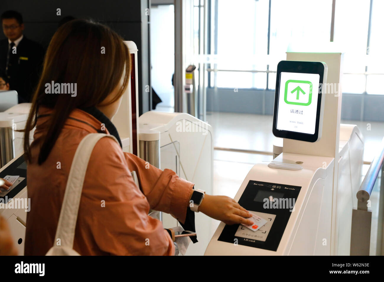 A passenger scans her boarding pass on a self-service boarding machine ...