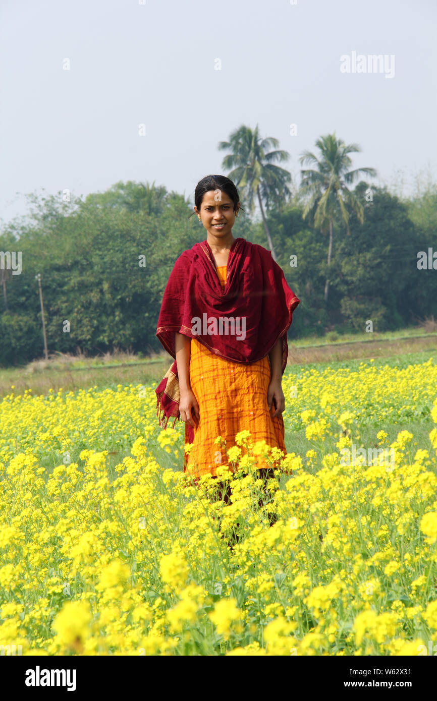 Rural woman standing in a mustard field Stock Photo - Alamy
