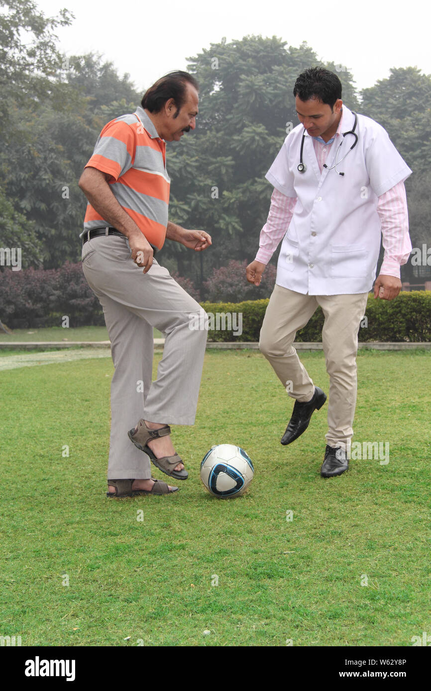 Physiotherapist with his patient playing football in a park Stock Photo ...