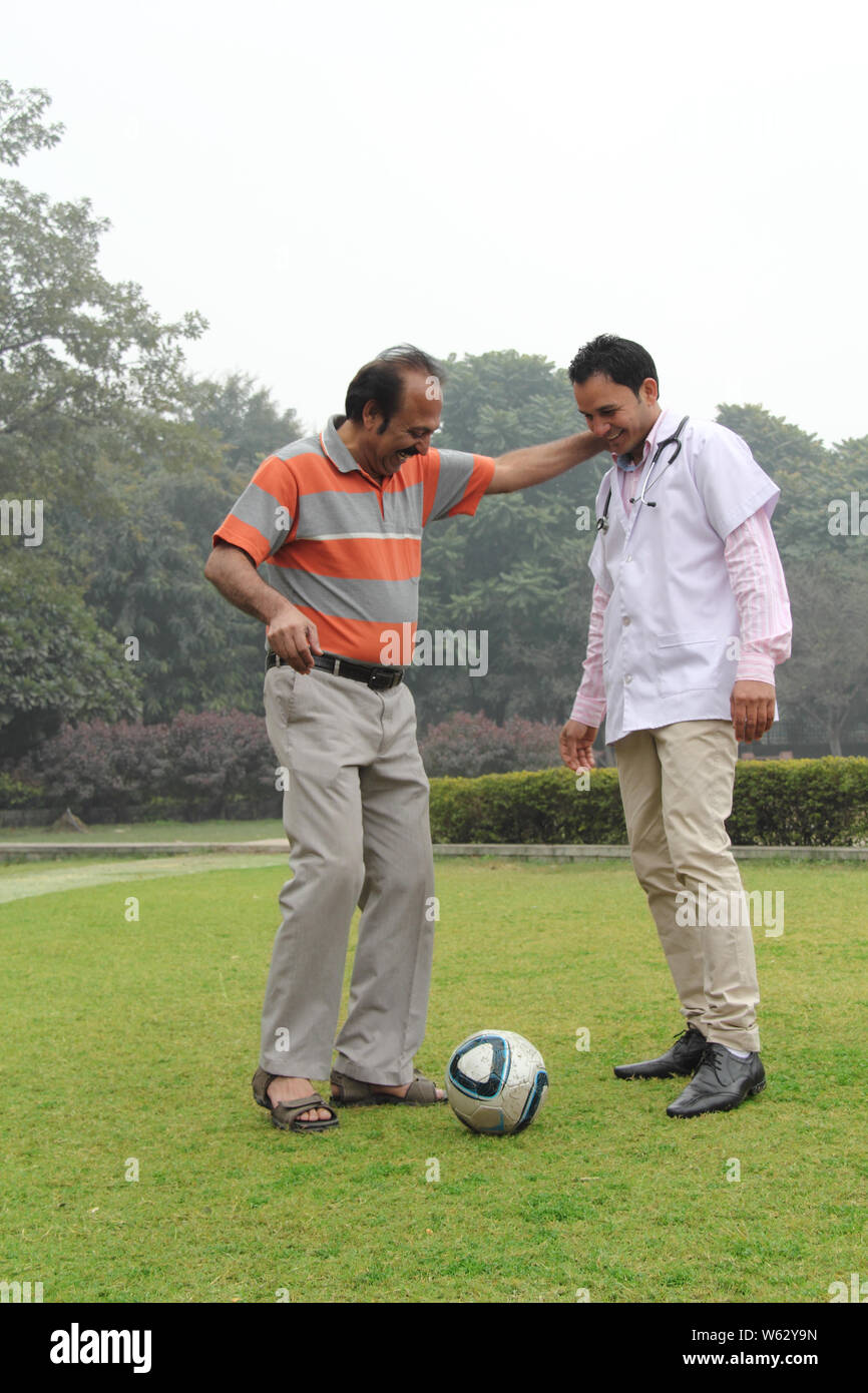 Patient playing football with a physiotherapist Stock Photo - Alamy