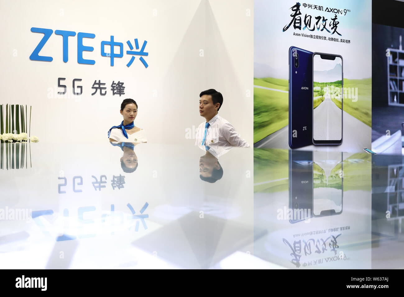 Chinese employees are seen at the stand of ZTE during the China ...