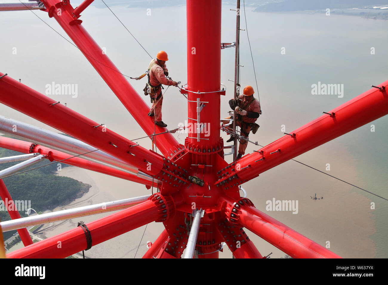 Workers labor at the world's tallest transmission towers that support the 2,656-meter-long power ...