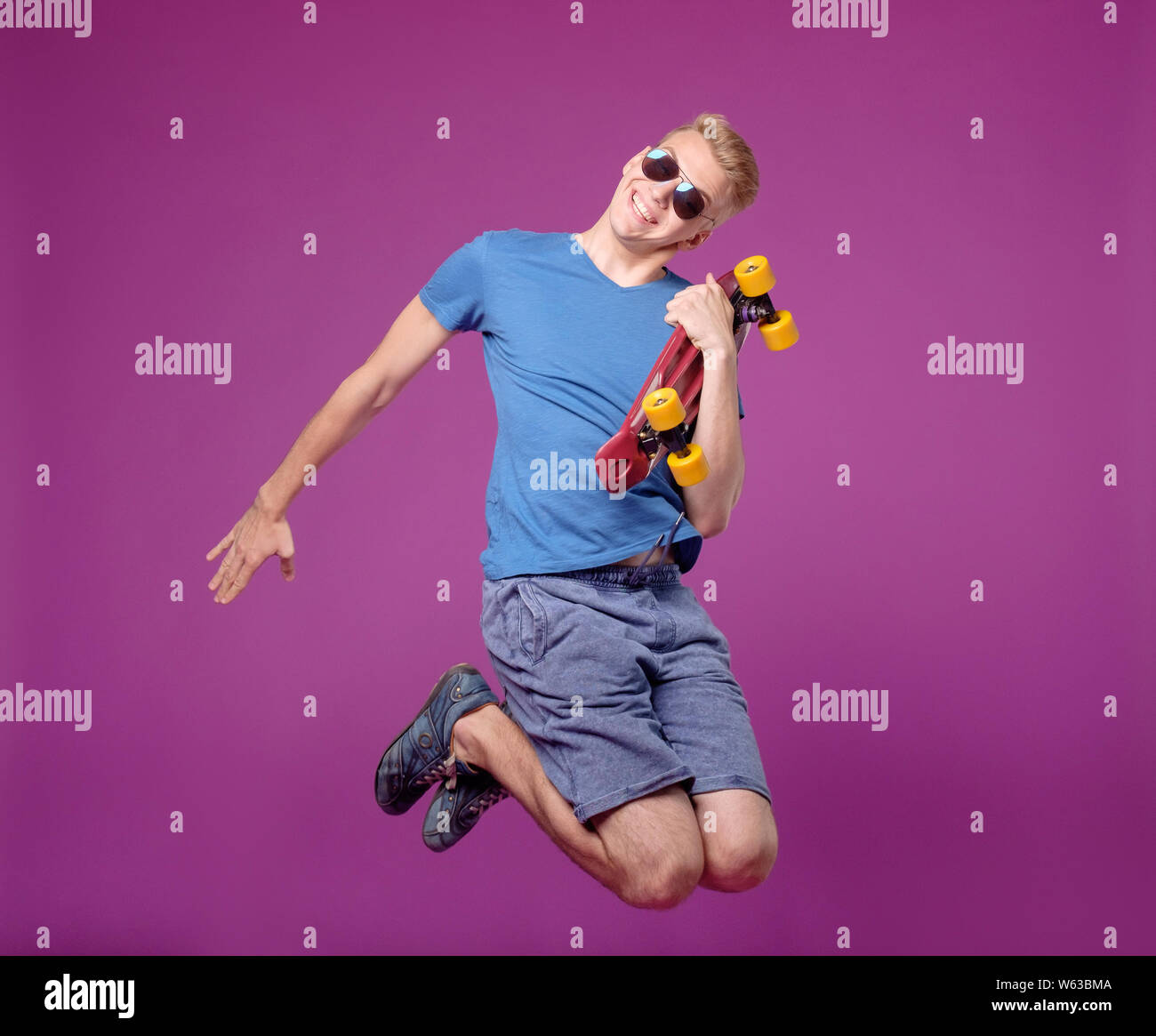 man jump with skate board in hand on purple background, penny little ...