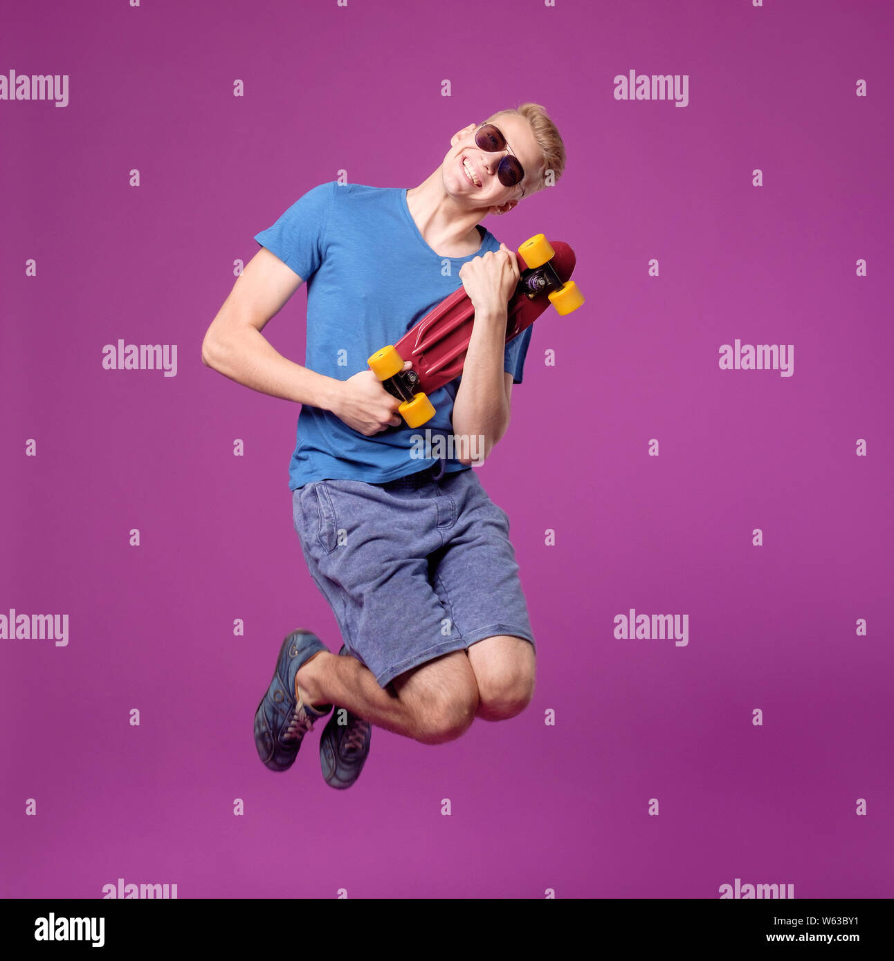 man jump with skate board in hand on purple background, penny little ...