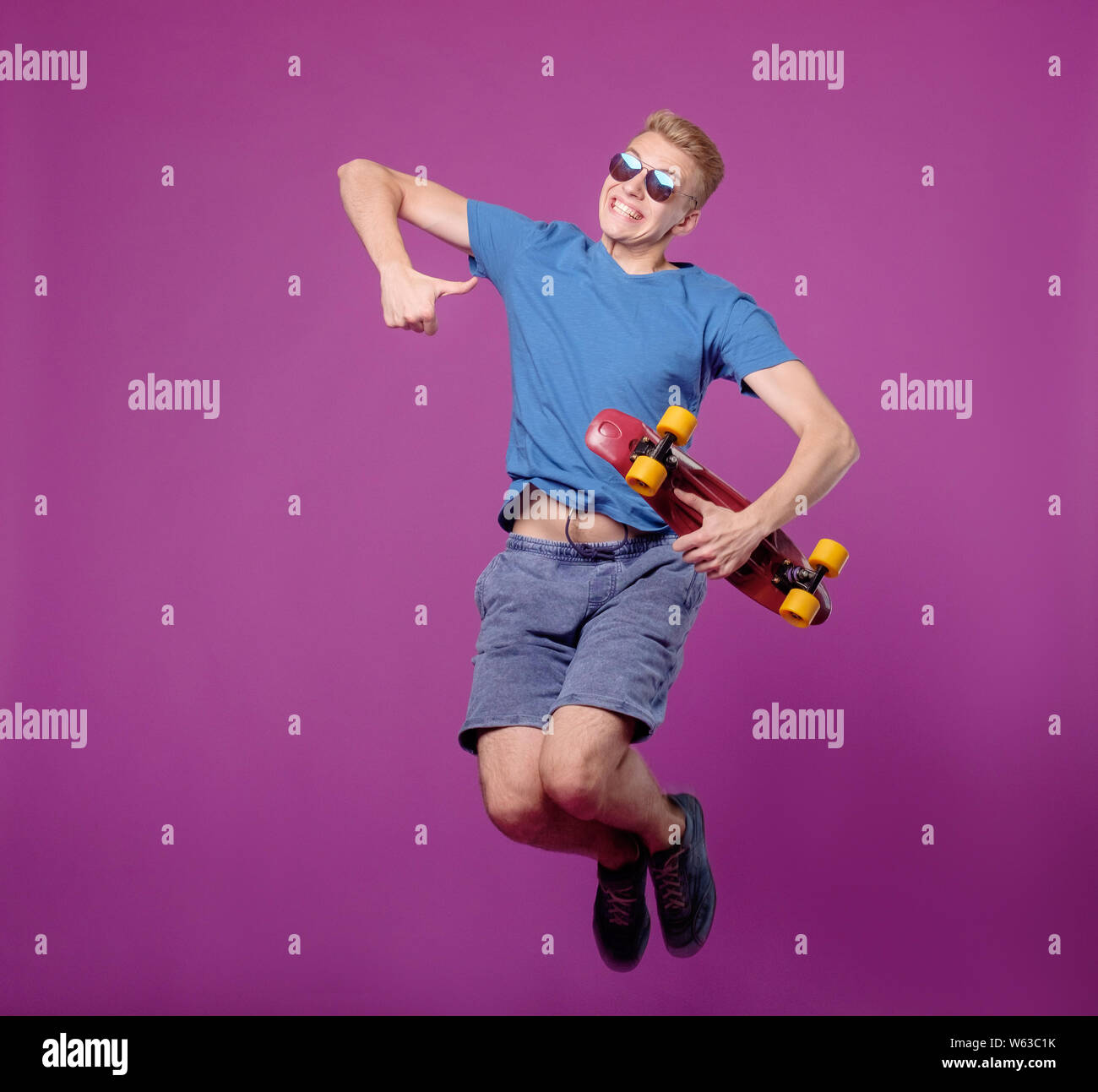 man jump with skate board in hand on purple background, penny little ...