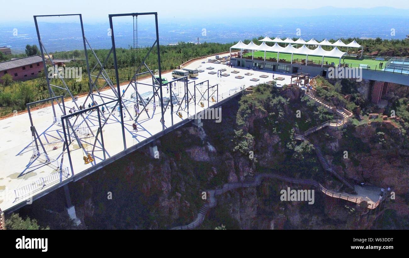 Tourists experience swings over the edge of a vertical cliff in a ...