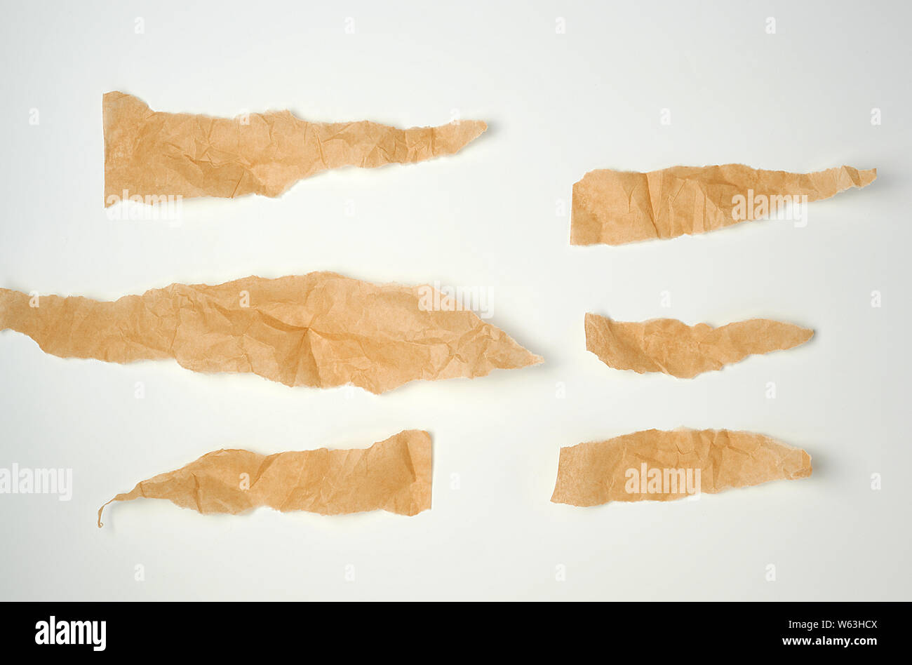 torn brown pieces of parchment paper on a white background, flat lay ...