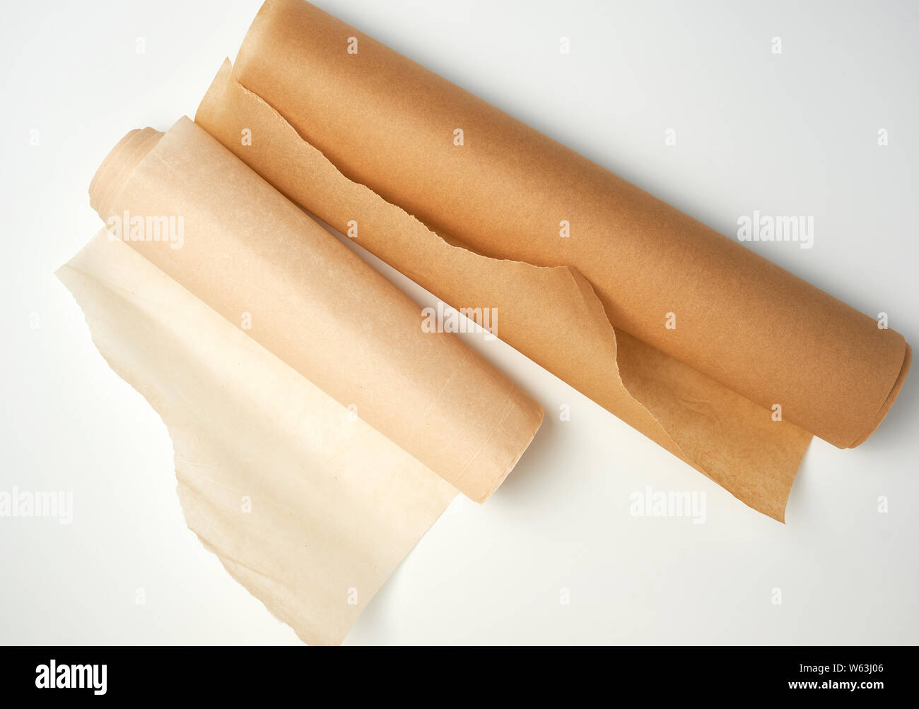 two rolls of brown parchment paper for baking on a white background ...