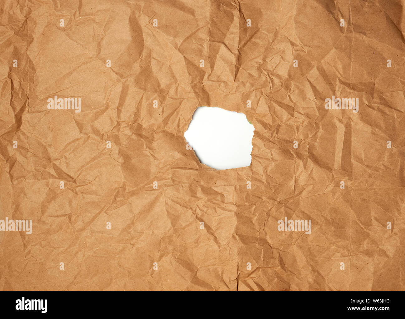 round torn hole in brown paper, white background, close up Stock Photo ...