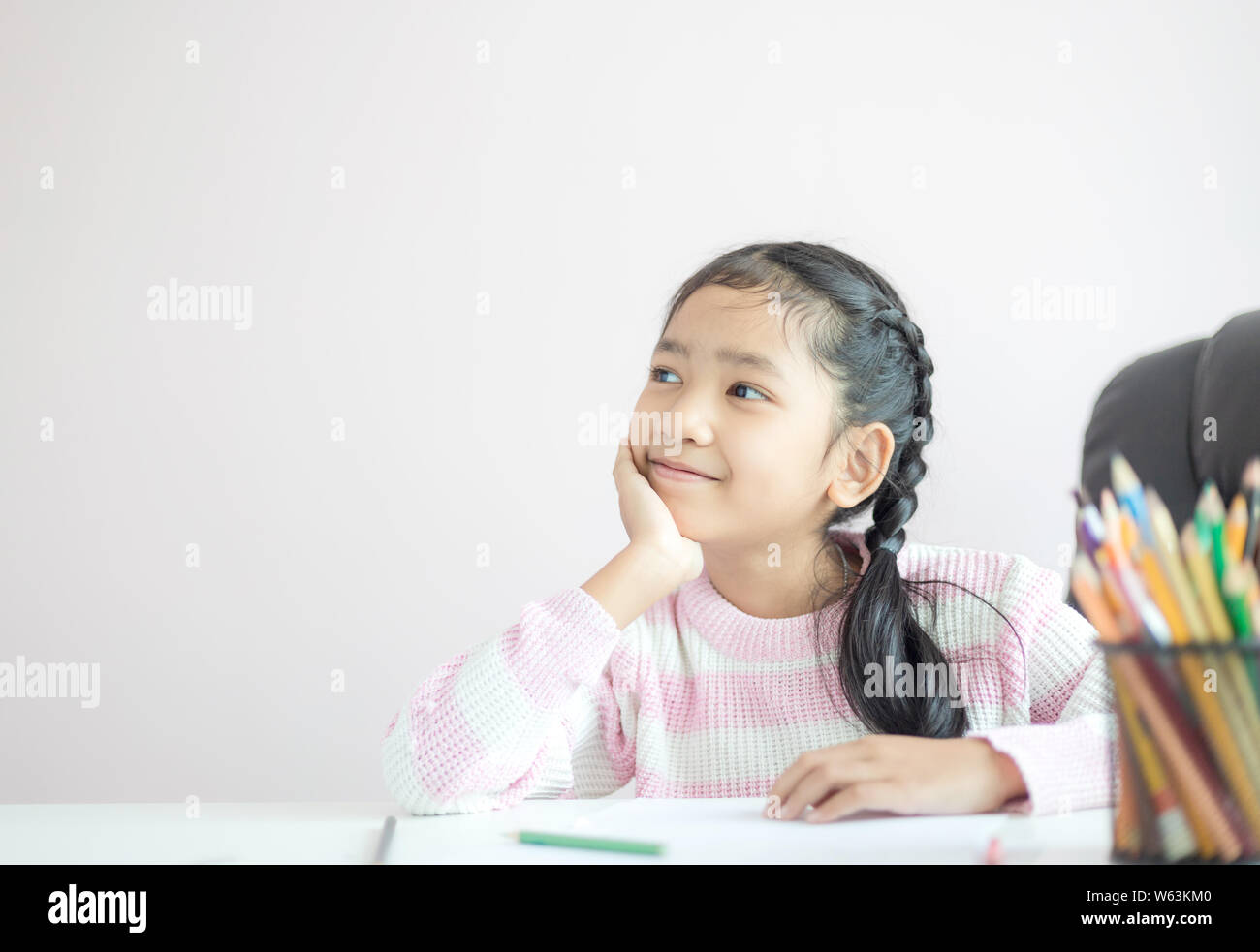 Portrait little Asian girl sitting on the chin and smile with happiness ...