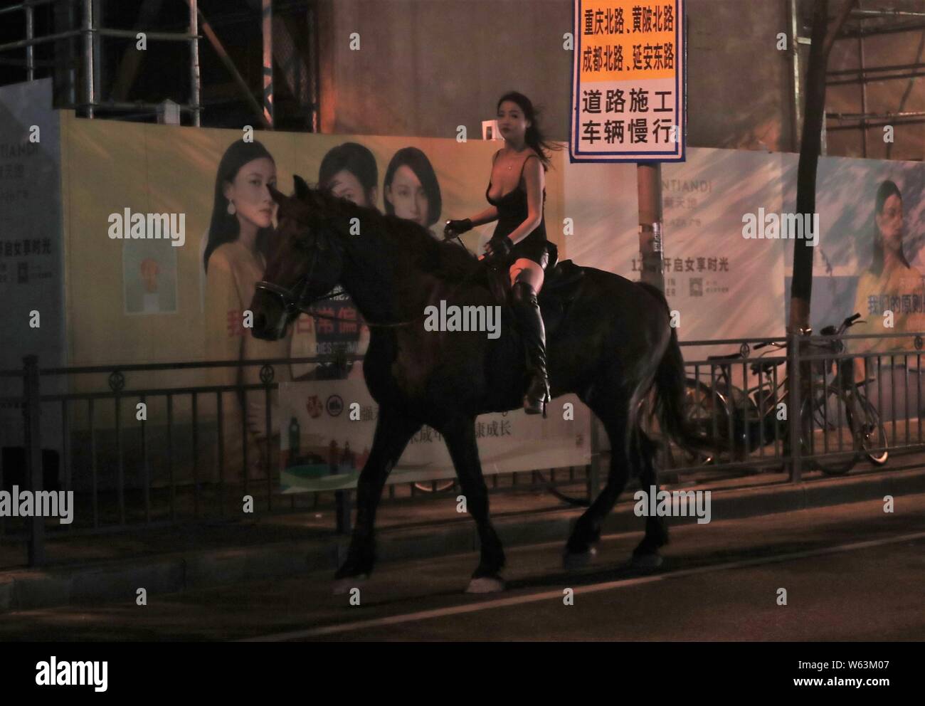 A Chinese girl rides on a horse wandering through the streets at night ...