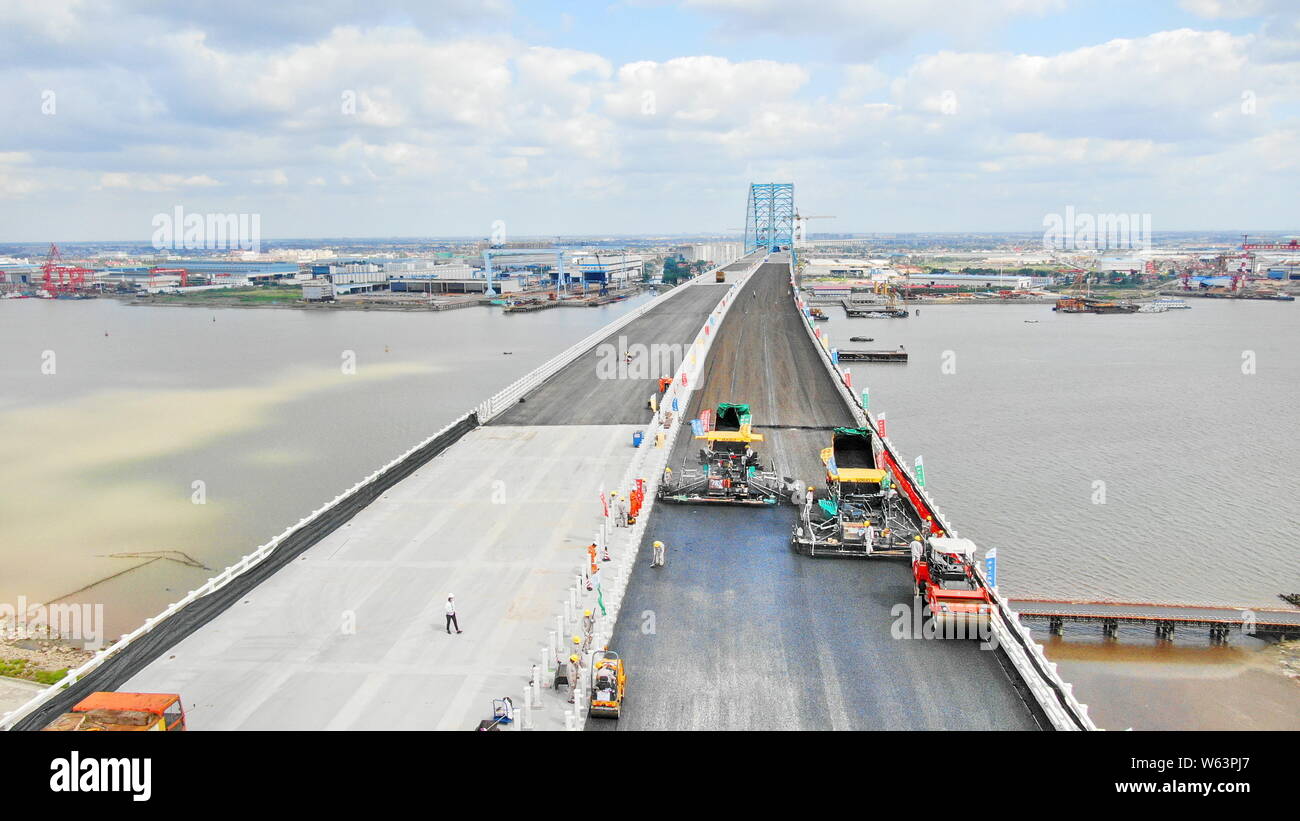 Chinese workers operate road paver to paint bitumen on the world's ...