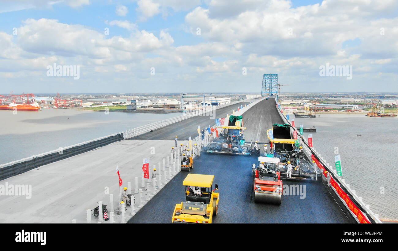 Chinese workers operate road paver to paint bitumen on the world's ...