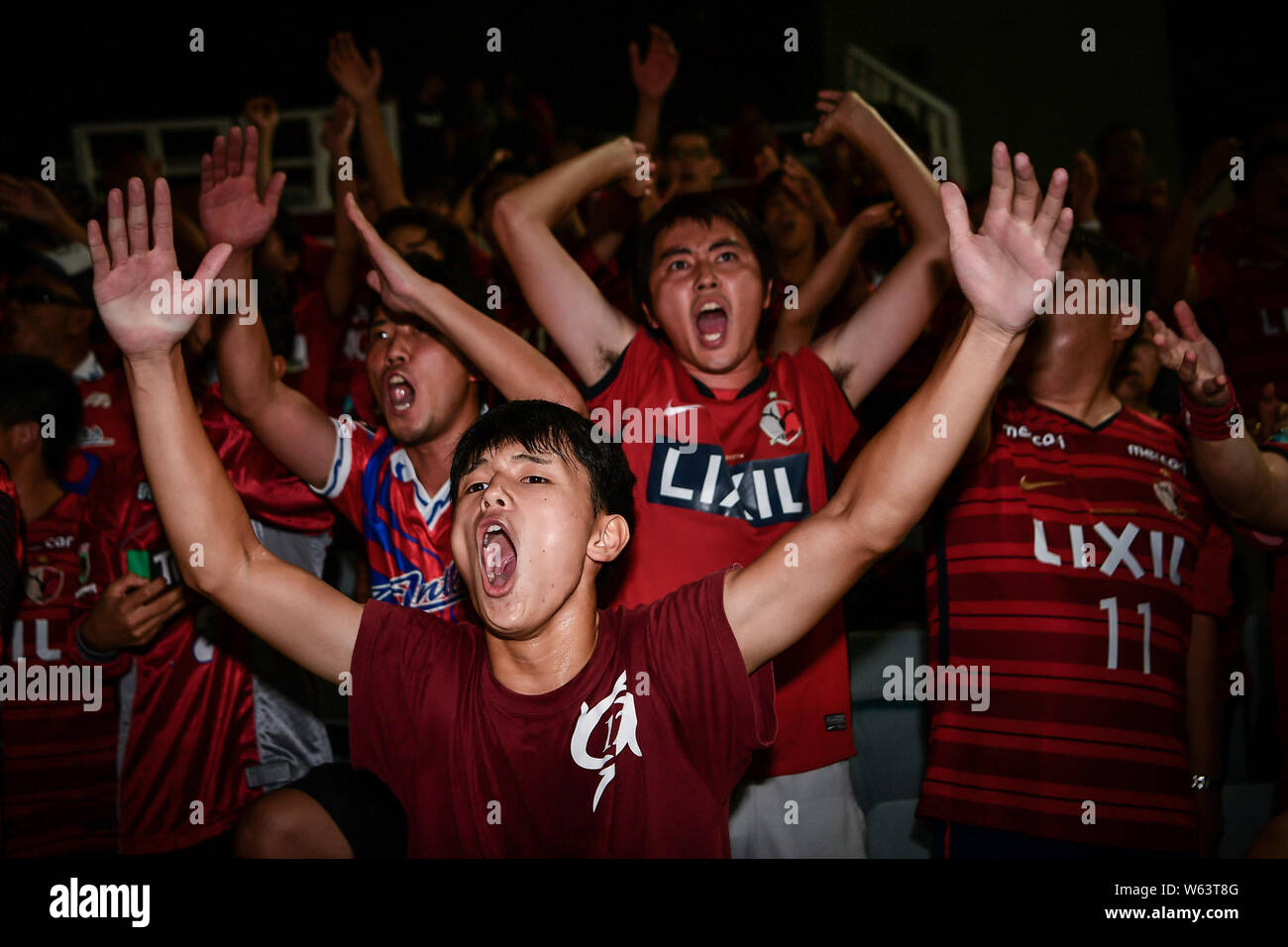Football fans wave flags and shout slogans to show support for Japan's Kashima Antlers in the ...
