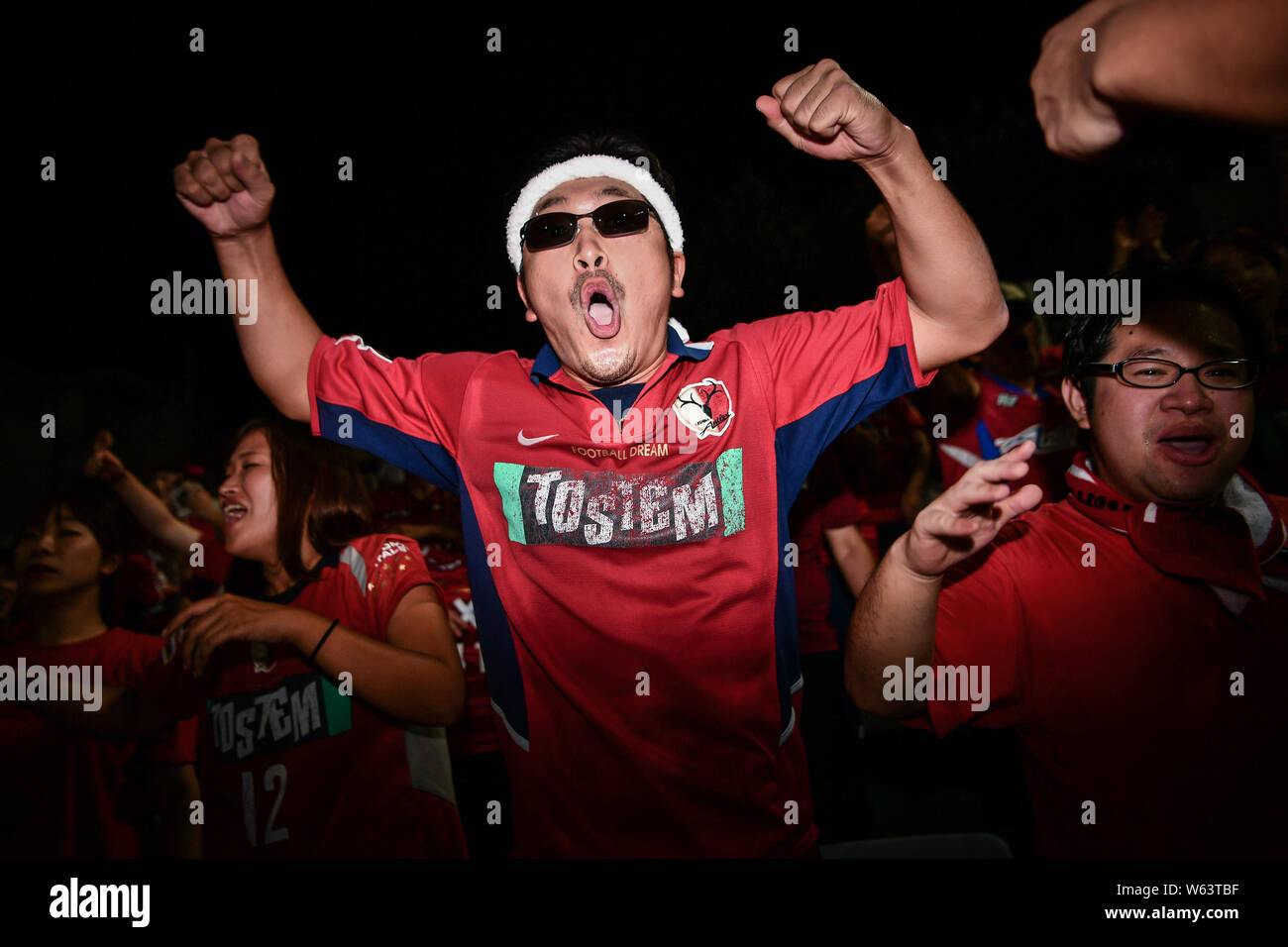 Football fans wave flags and shout slogans to show support for Japan's Kashima Antlers in the ...