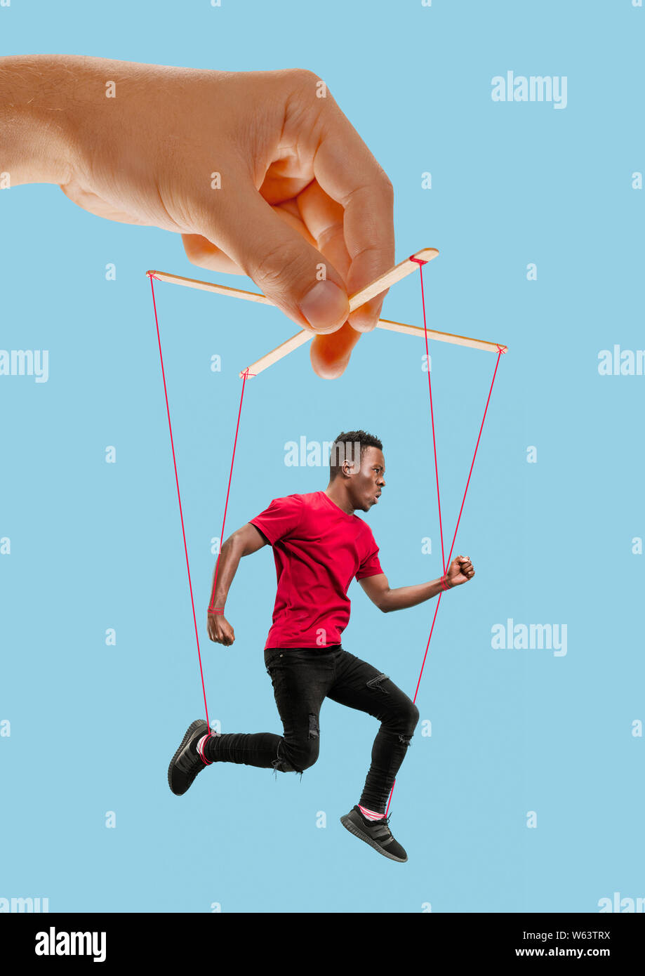 Man like a puppet in somebodies hands on blue background. Concept of ...
