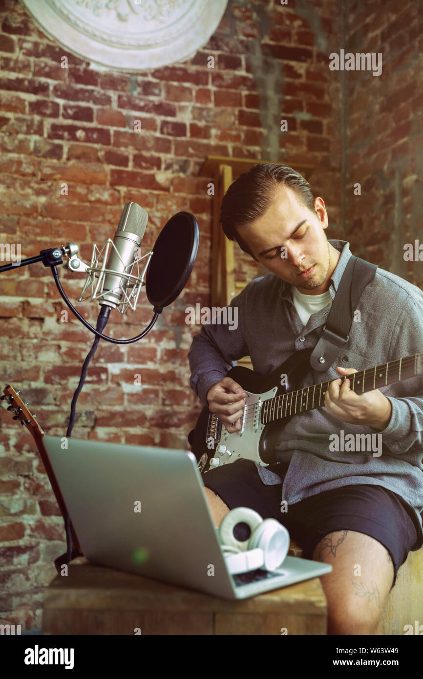Young man recording music video blog home lesson, playing guitar or ...