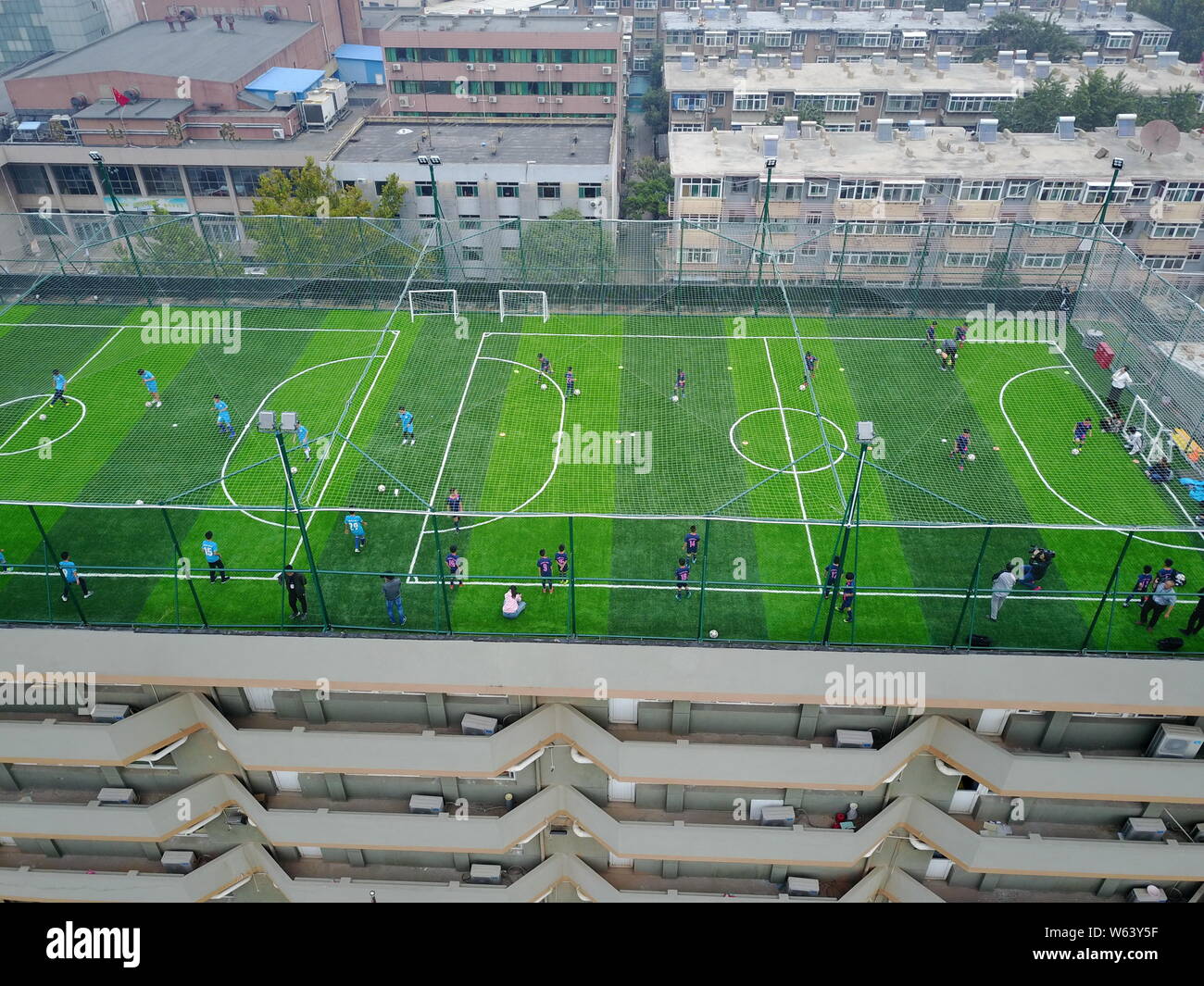 In this aerial view, children play football at a football stadium built ...
