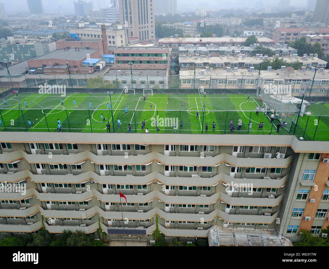 In this aerial view, children play football at a football stadium built ...