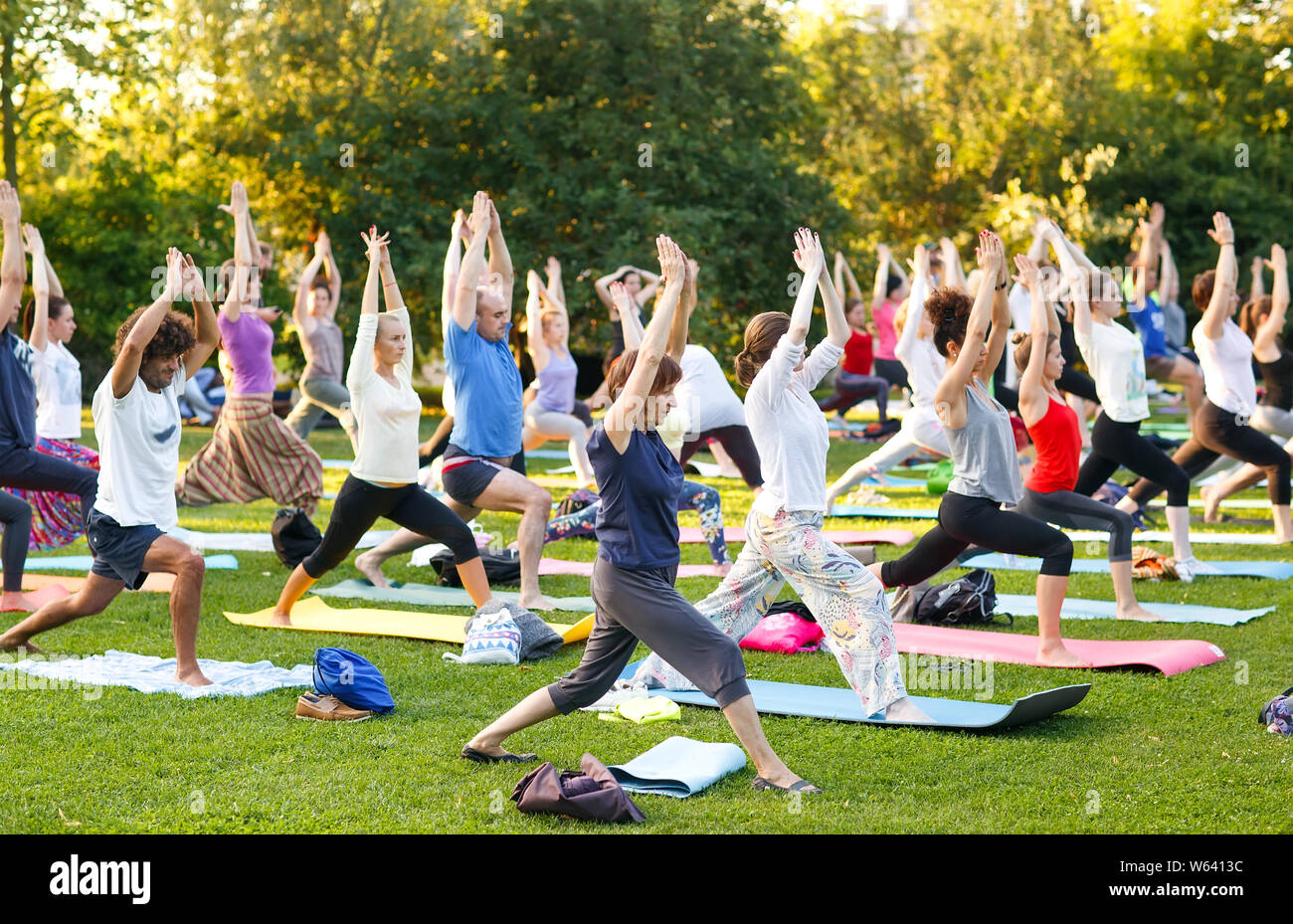 big group of adults attending a yoga class outside in park Stock Photo ...