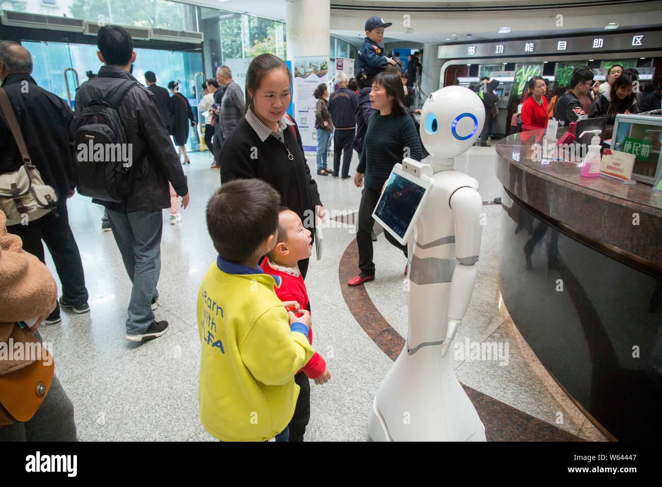 Chinese people look at a robot receptionist named Xiaoman in the ...