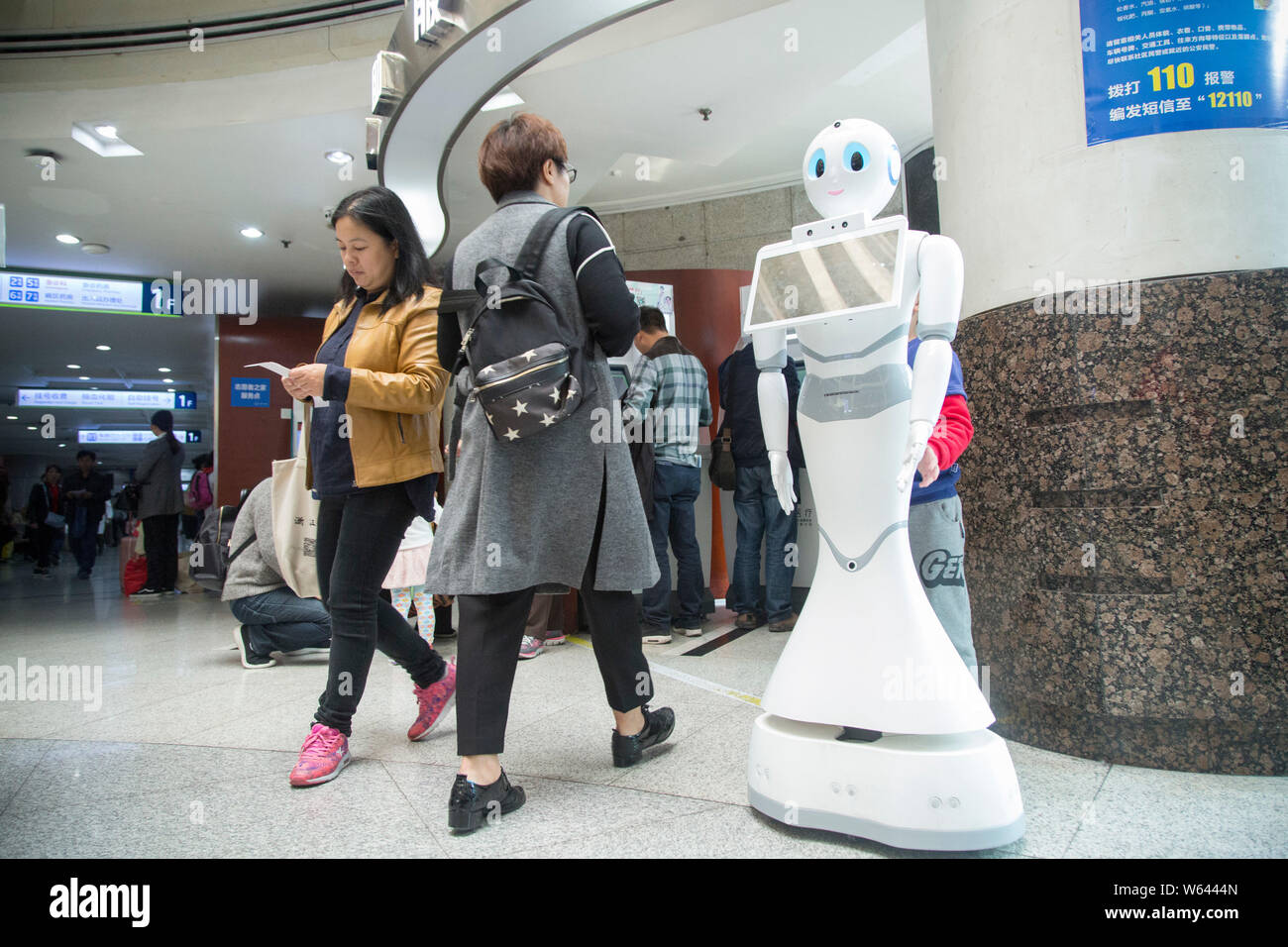 Chinese women walk past a robot receptionist named Xiaoman in the ...