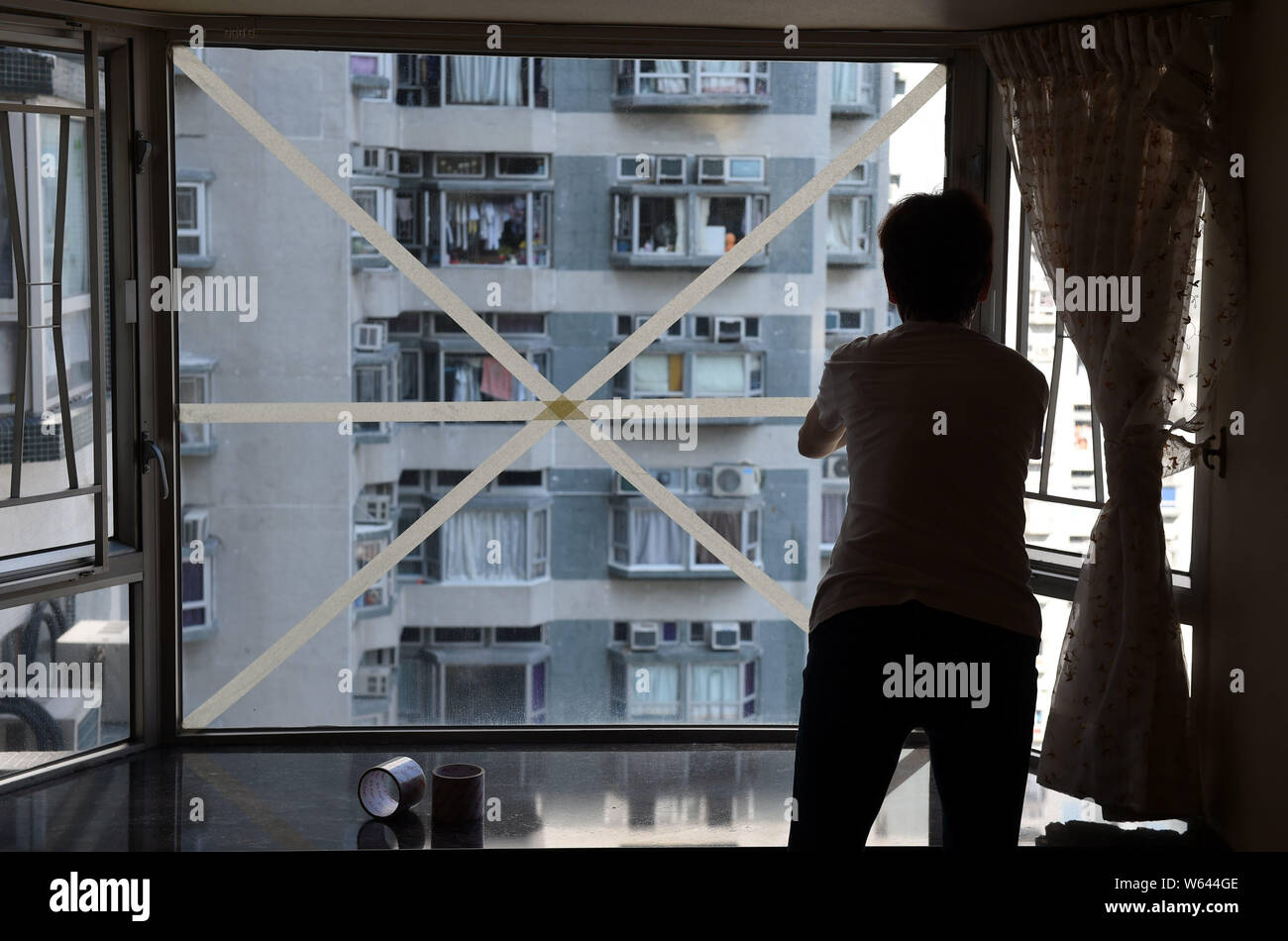 A citizen tapes up a window at her home in preparation for the Typhoon ...