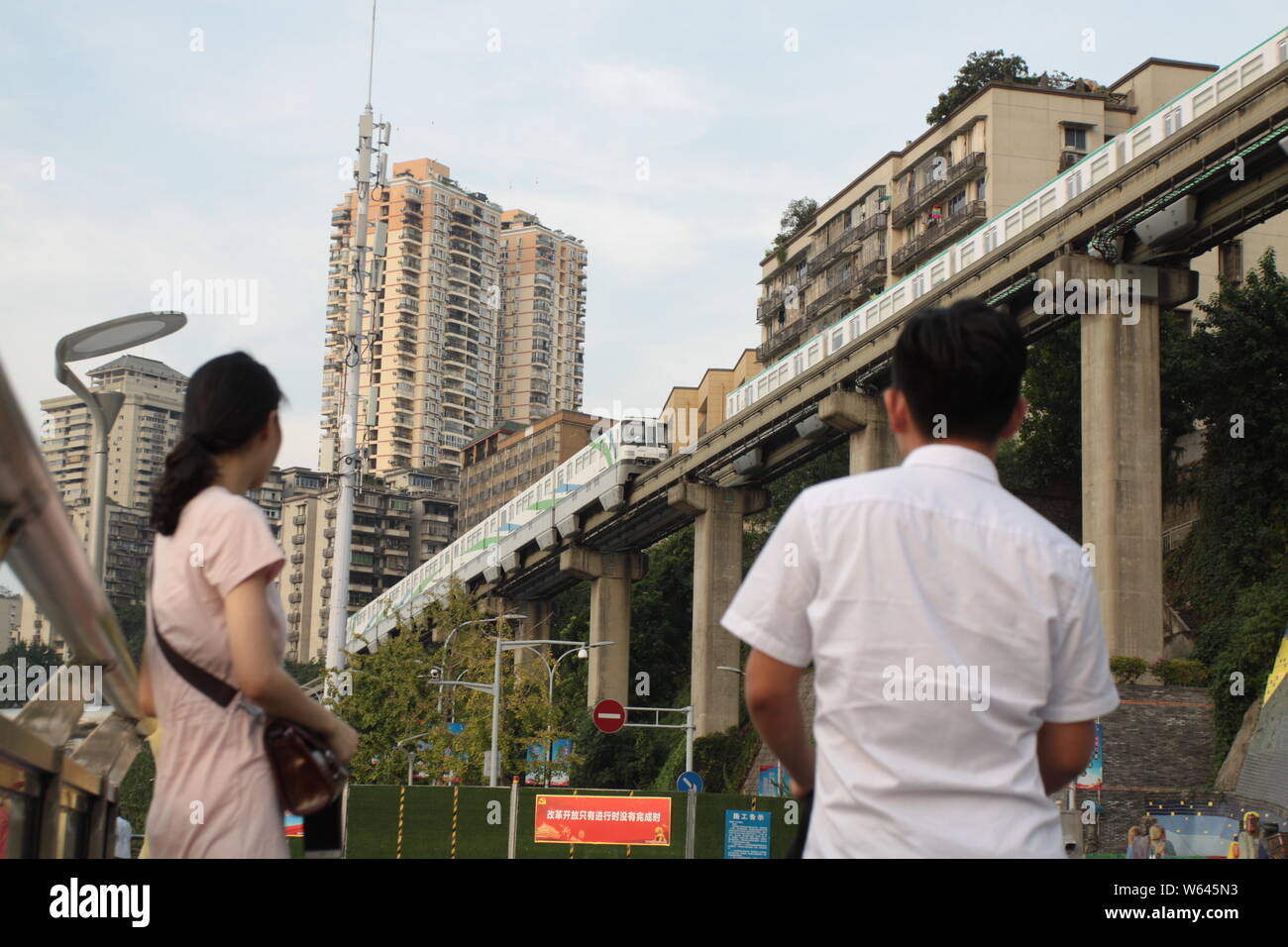 Visitors watch a monorail train of Chongqing Light Rail Line 2 running ...