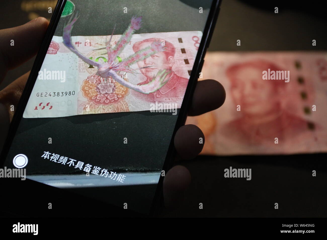 A Chinese mobile phone user scans a 100-yuan RMB (renminbi) banknote ...