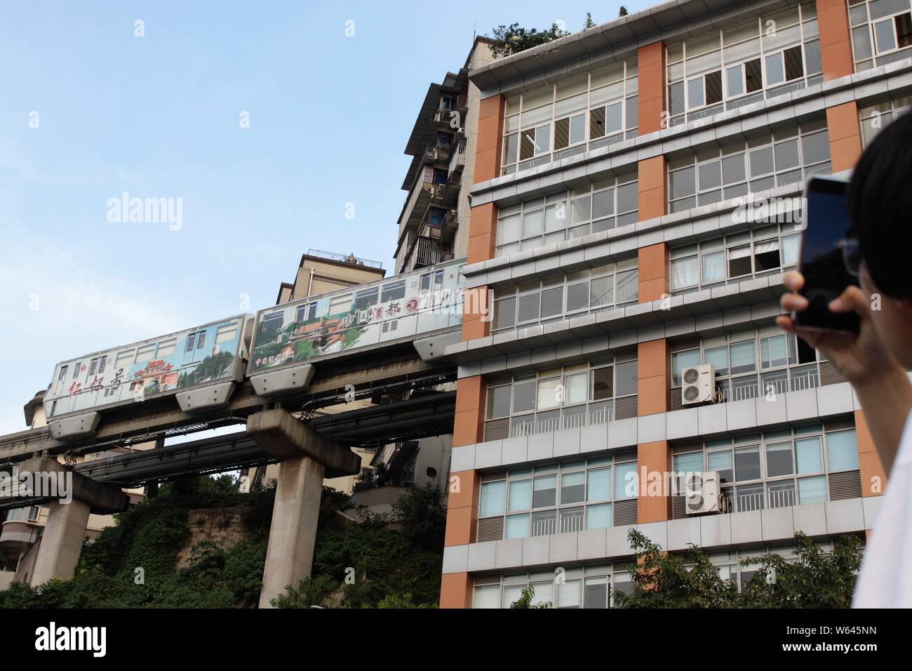 A visitor takes photos of a monorail train of Chongqing Light Rail Line ...