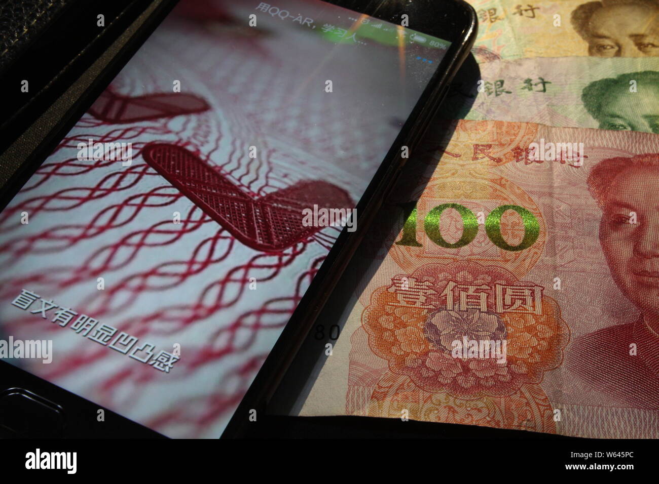 A Chinese mobile phone user scans a 100-yuan RMB (renminbi) banknote ...