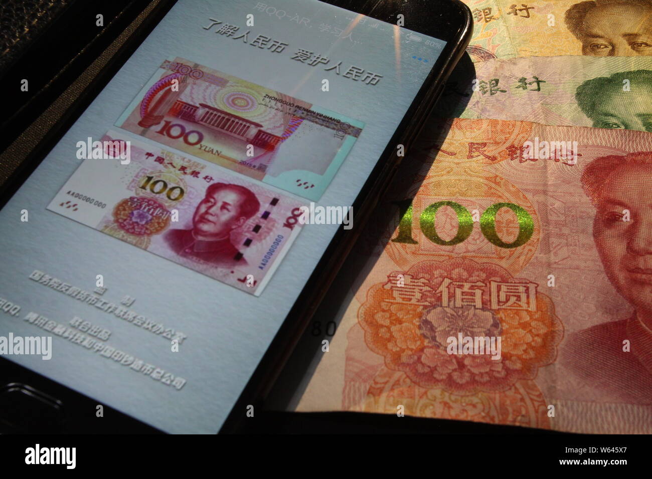 A Chinese mobile phone user scans a 100-yuan RMB (renminbi) banknote ...