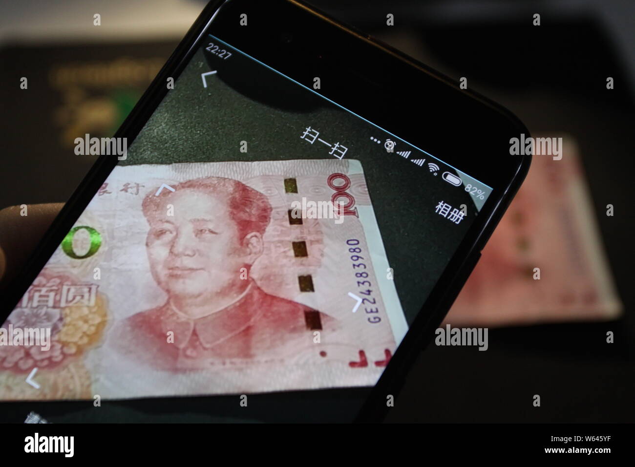 A Chinese mobile phone user scans a 100-yuan RMB (renminbi) banknote ...