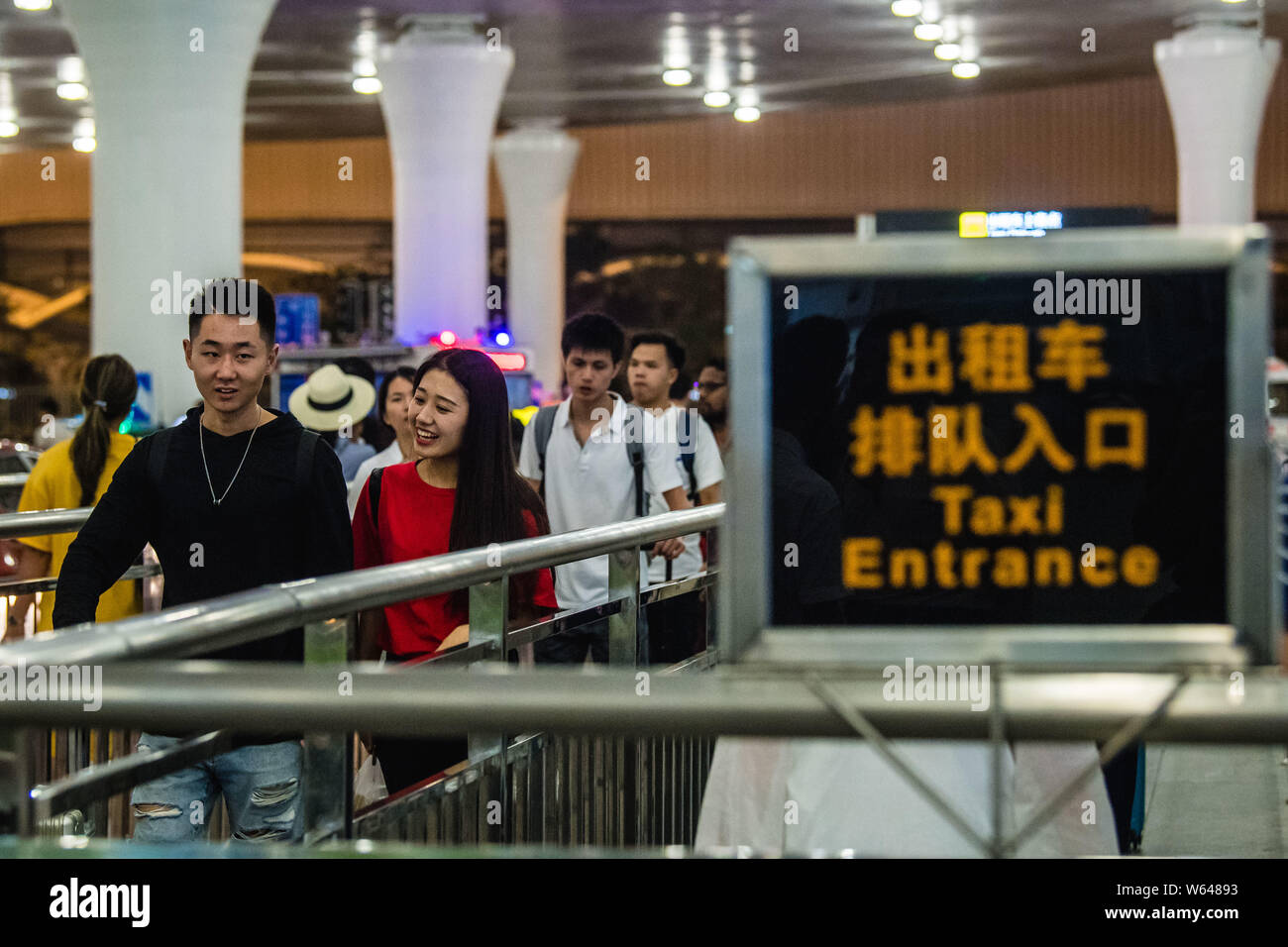 Passengers wait in a long queue at the taxi pick-up stand at the ...