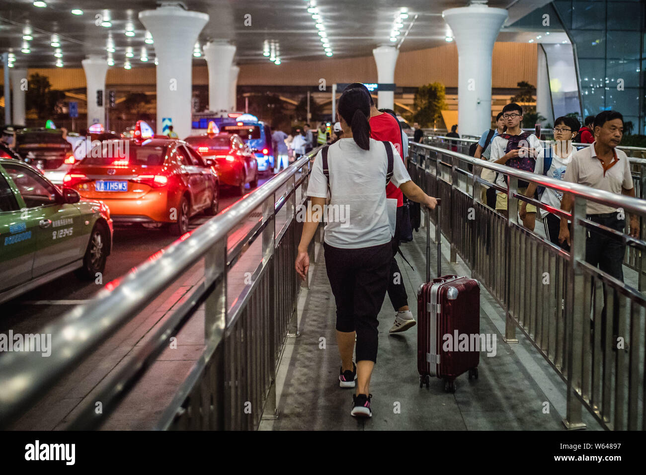 Passengers wait in a long queue at the taxi pick-up stand at the ...