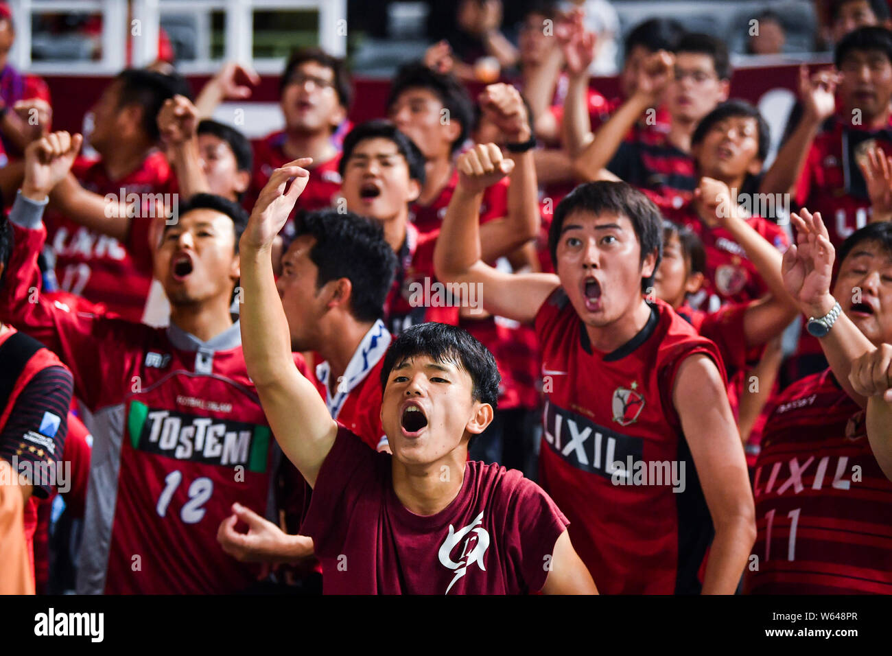 Football fans wave flags and shout slogans to show support for Japan's Kashima Antlers in the ...