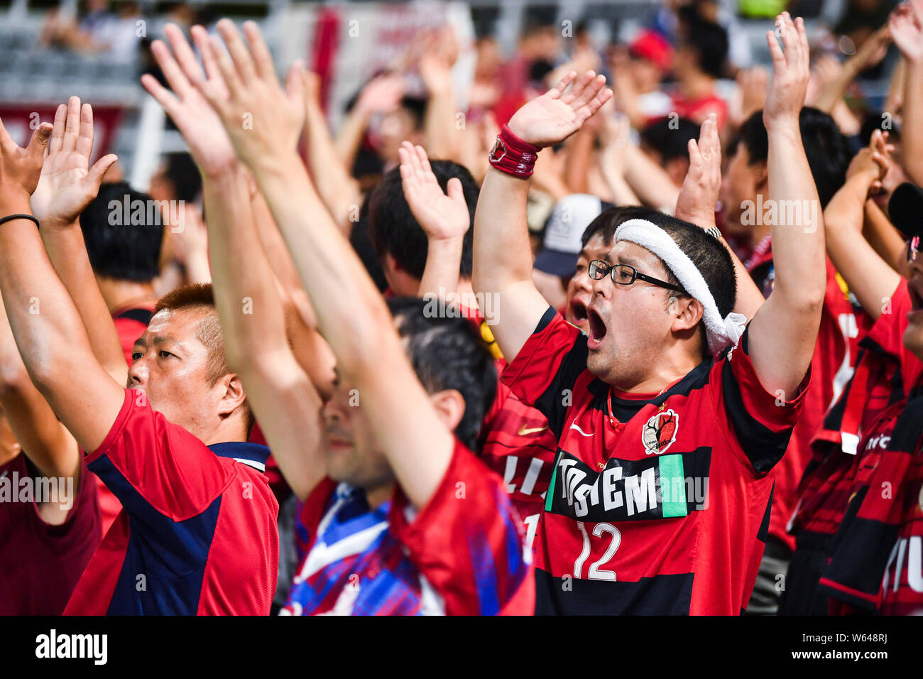 Football fans wave flags and shout slogans to show support for Japan's Kashima Antlers in the ...